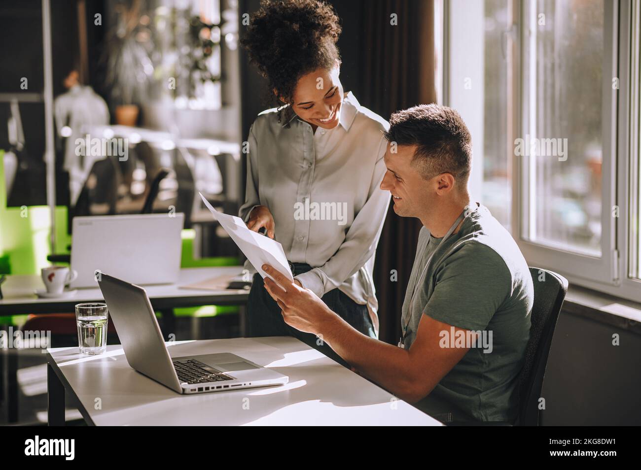 Cheerful office worker demonstrating documents to her boss Stock Photo ...