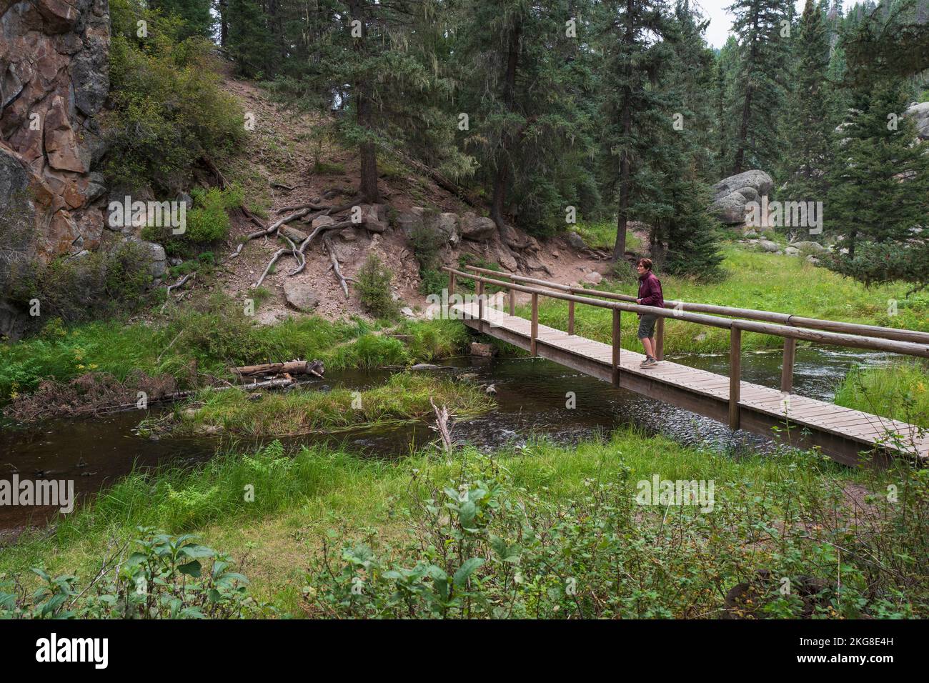 USA, New Mexico, Jemez Mountains, Woman walking on wooden bridge over ...