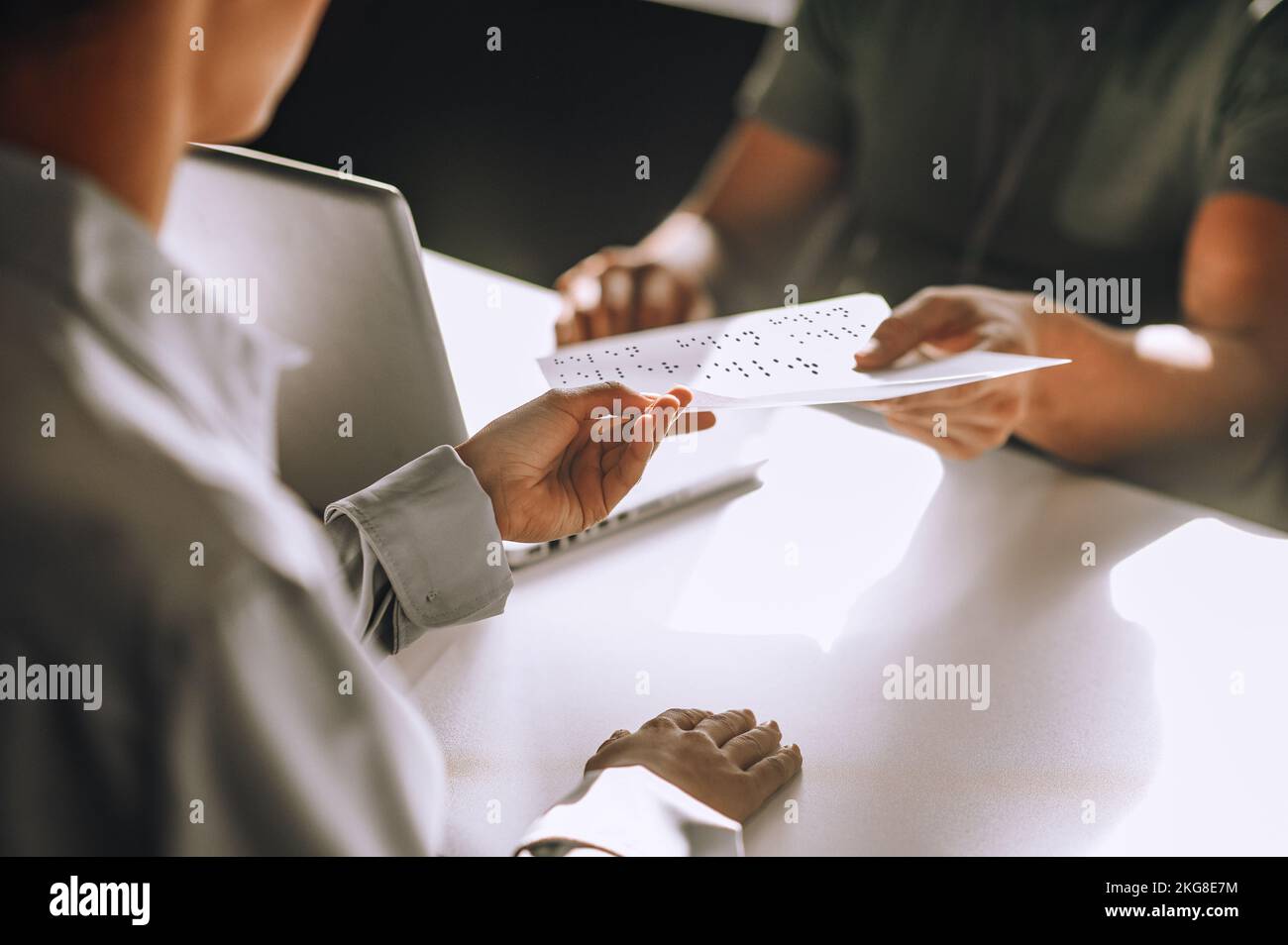 Employee handing her coworker a sheet of Braille paper Stock Photo - Alamy