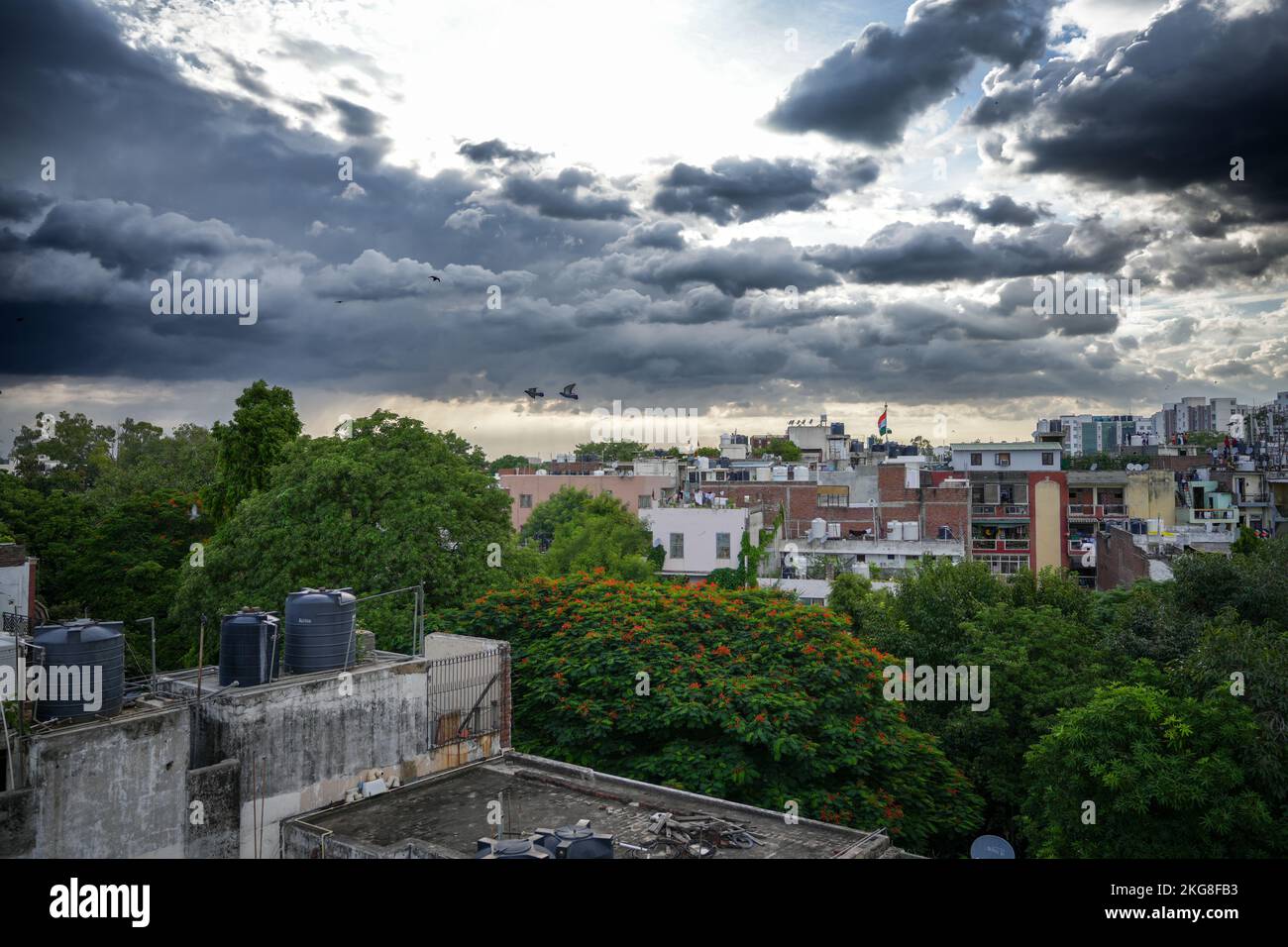 A landscape of residential buildings surrounded by trees on a stormy ...