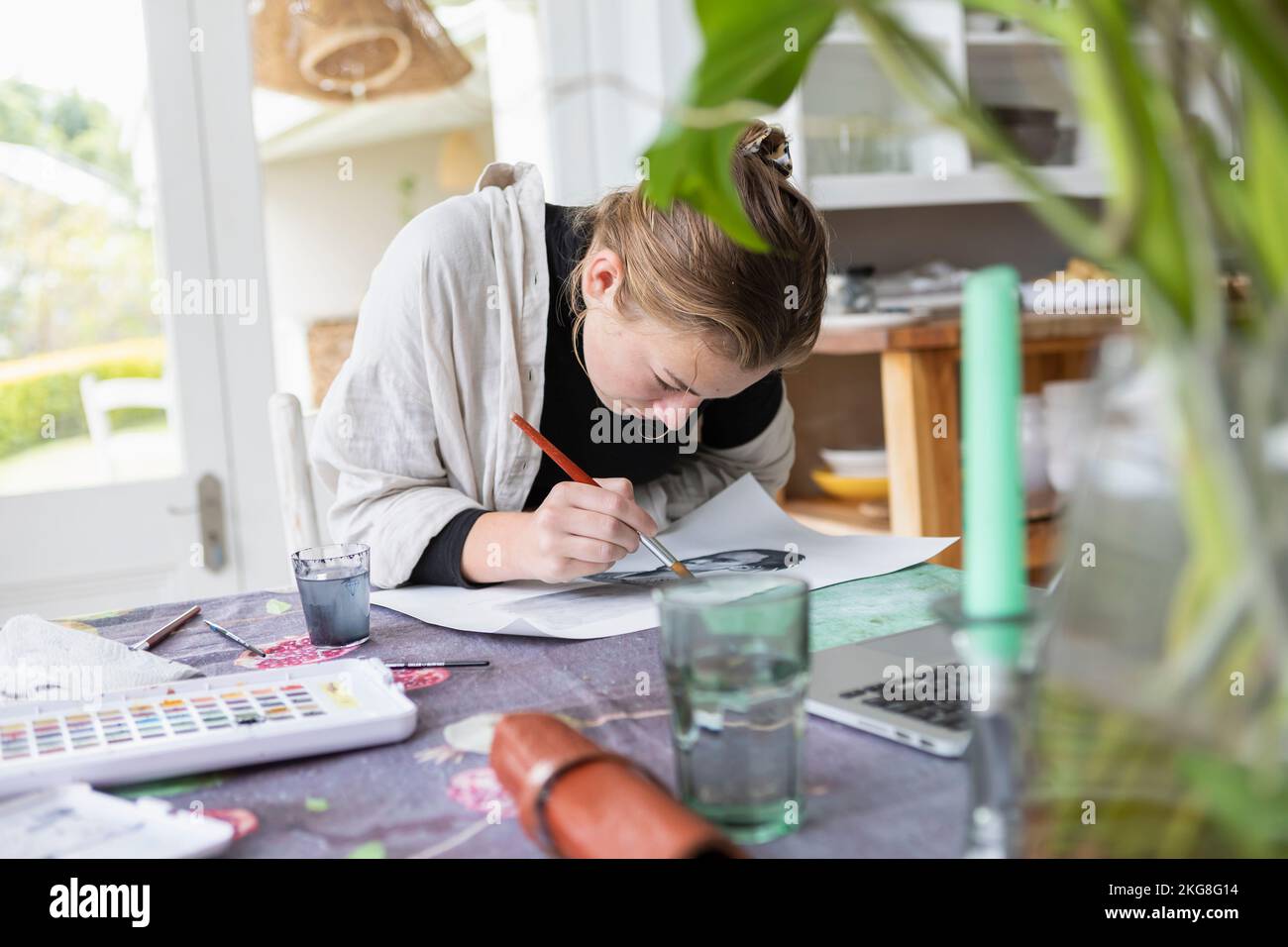 Teenage girl (16-17) artist working in her studio painting with ...