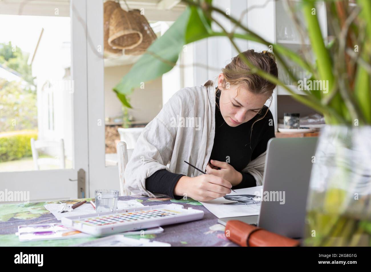 Teenage girl (16-17) artist working in art studio doing a watercolor ...