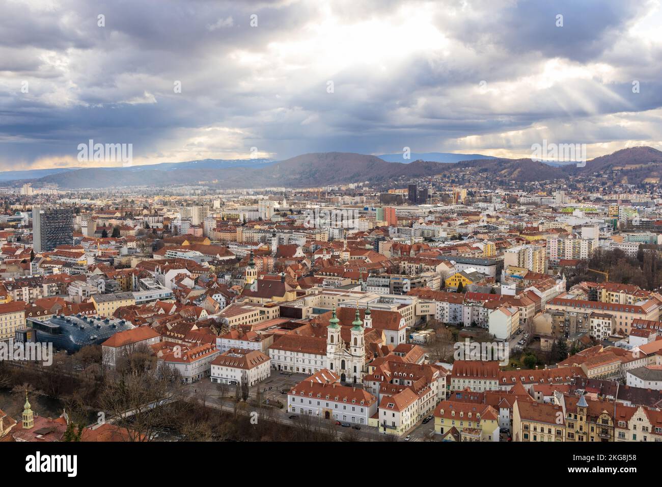 Graz cityscape with mountains in the background. Rays of sunshine break ...