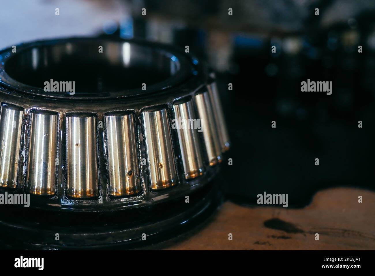 Close-up of a tapered roller bearing in grease on a dark industrial ...