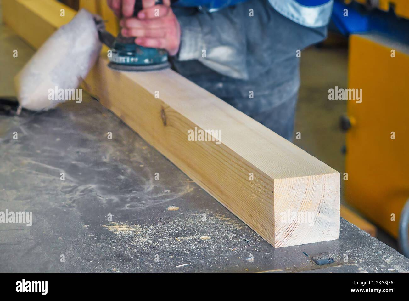 Professional woodworker grinds wooden bar on workbench in carpentry ...