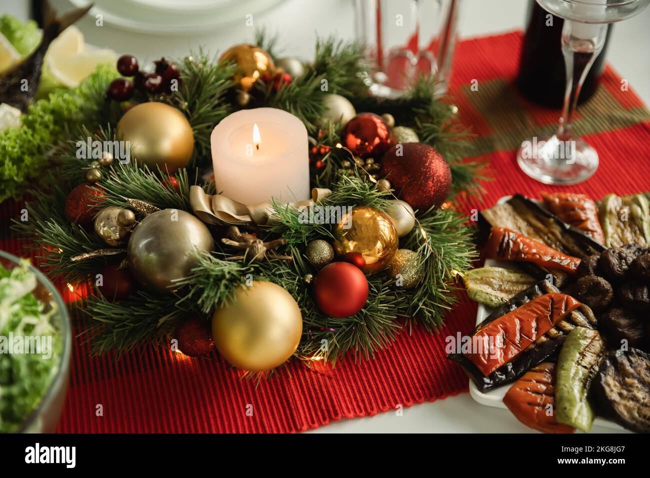Christmas wreath with burning candle and baubles near grilled ...