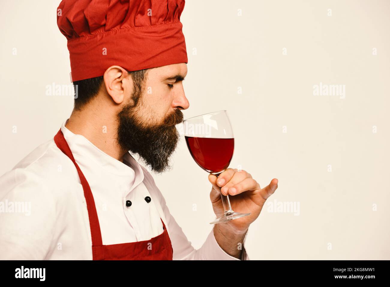 Cook with serious face in burgundy uniform drinks alcohol Stock Photo ...