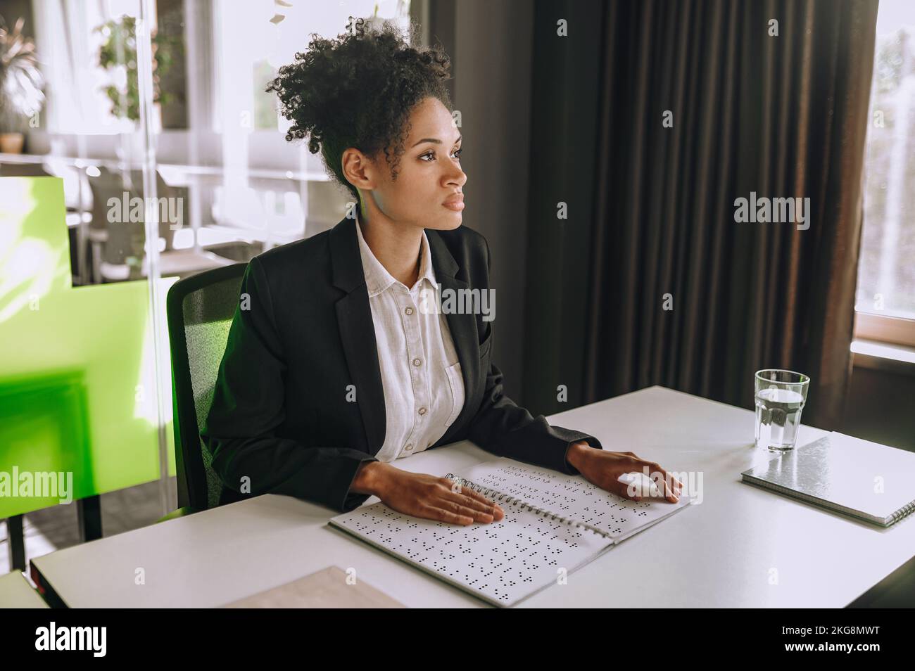 Visually impaired office worker seated at the table using Braille Stock ...