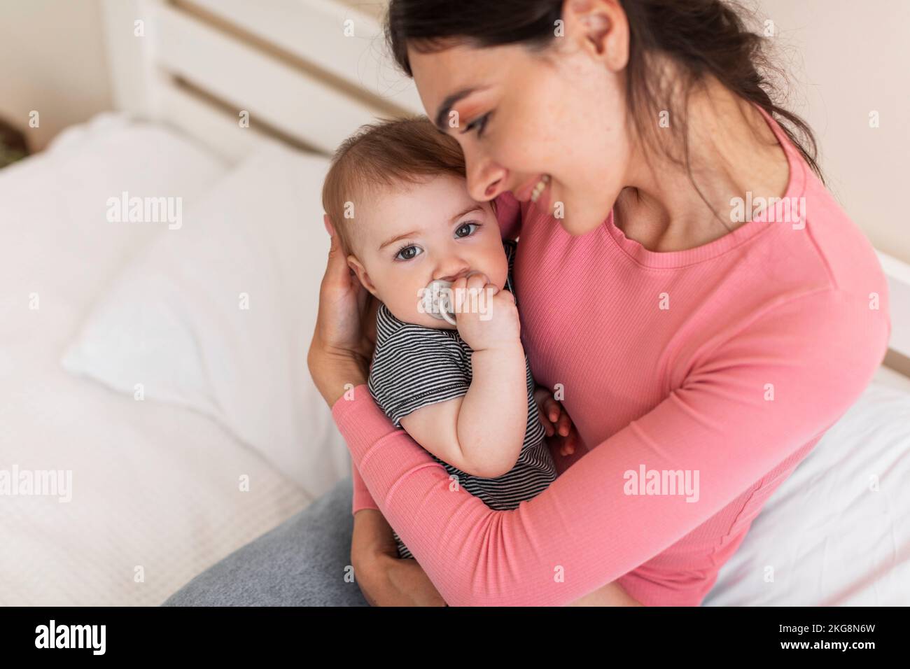 Loving mother cuddling and resting with her infant daughter on bed, mom ...