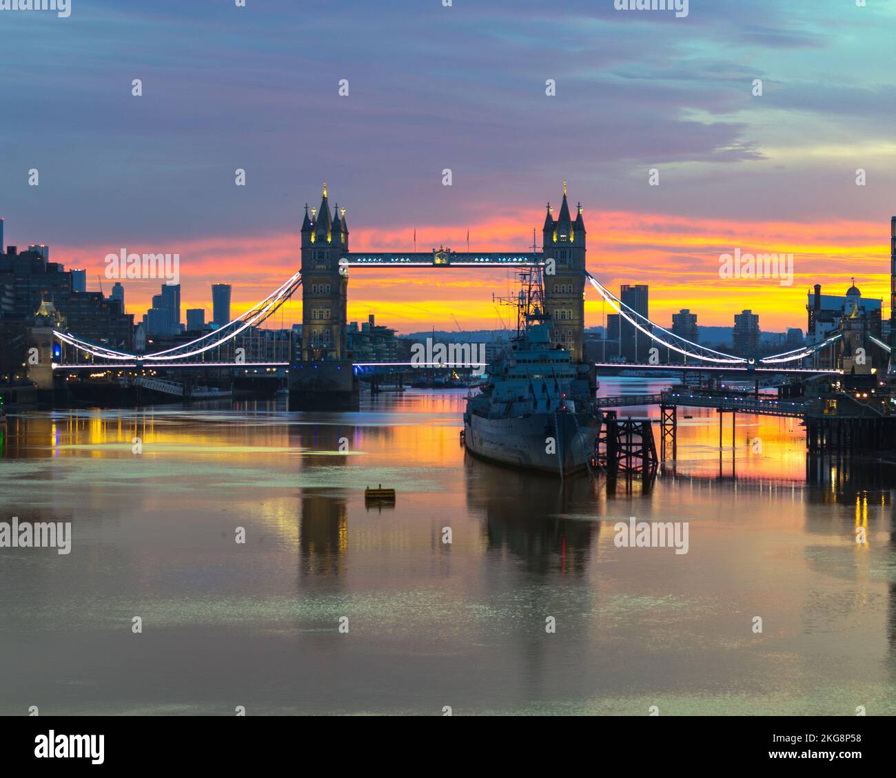A golden sunrise over the River Thames with tower bridge and HMS Belfast, Long exposure Stock ...