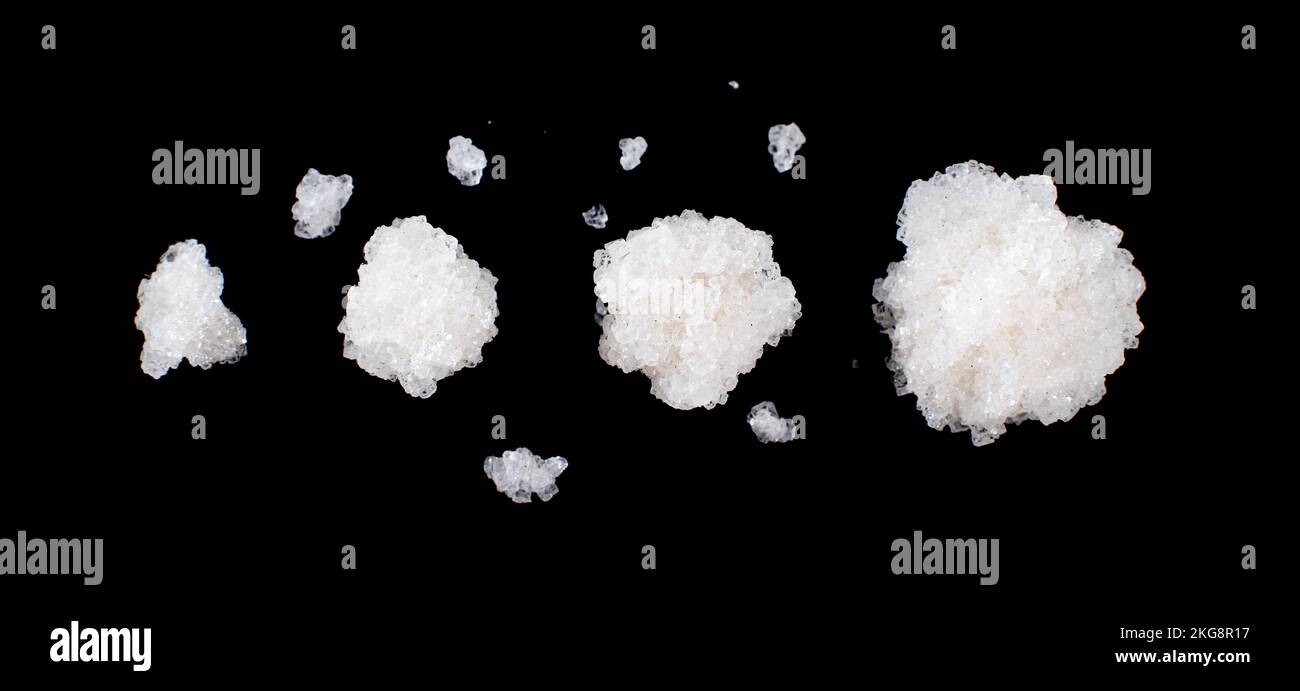 Sea salt lies on a black background close-up. Sea salt granules of ...