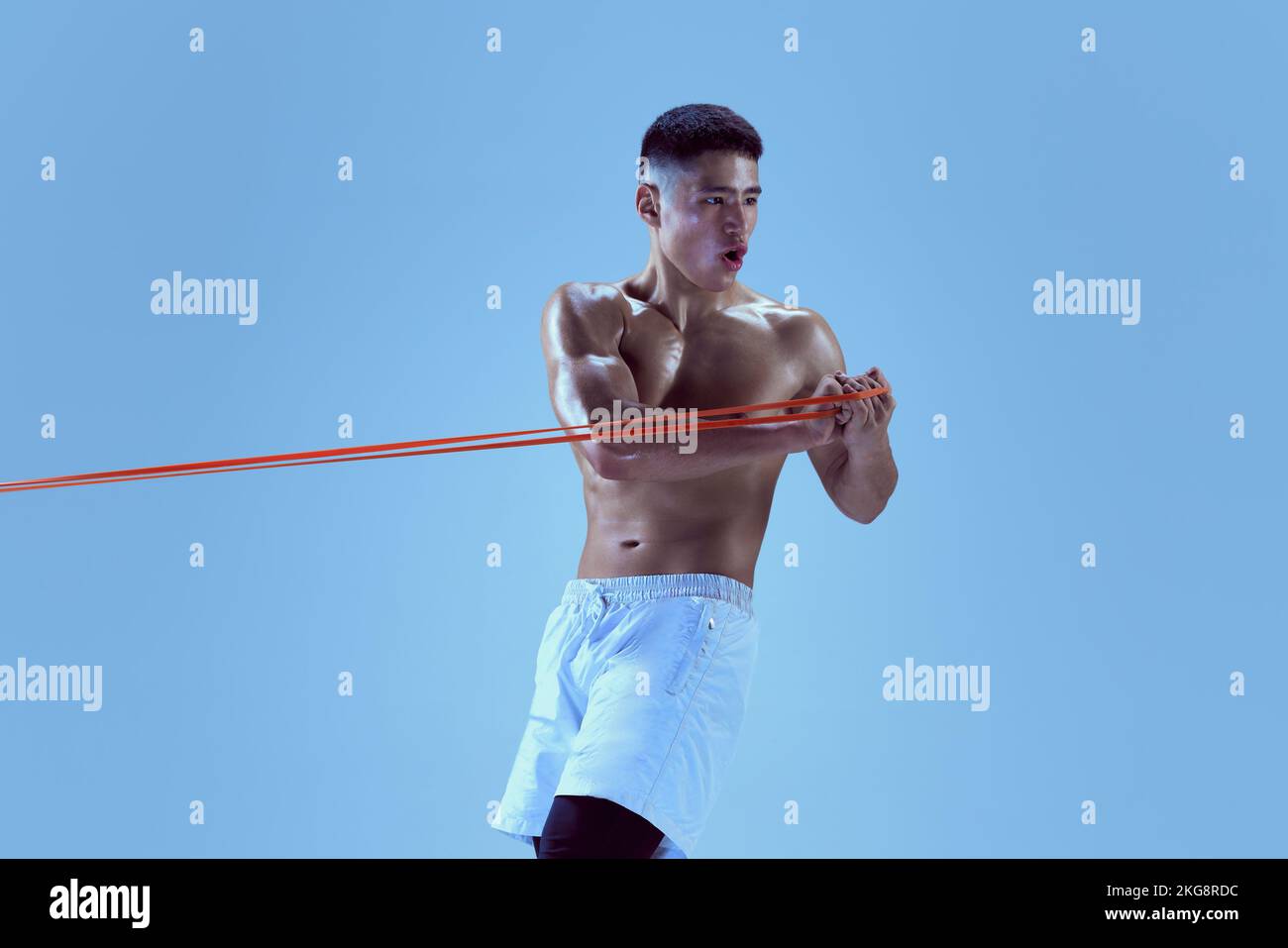 Portrait of young muscular man training with sports expander isolated ...