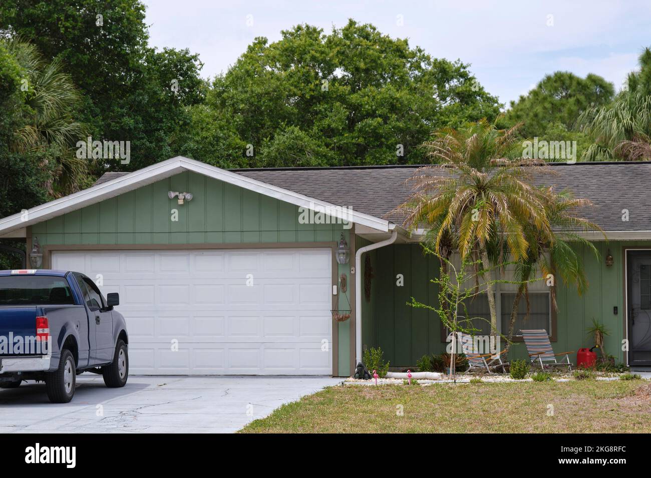Vehicle parked in front of wide garage double door on paved driveway of ...