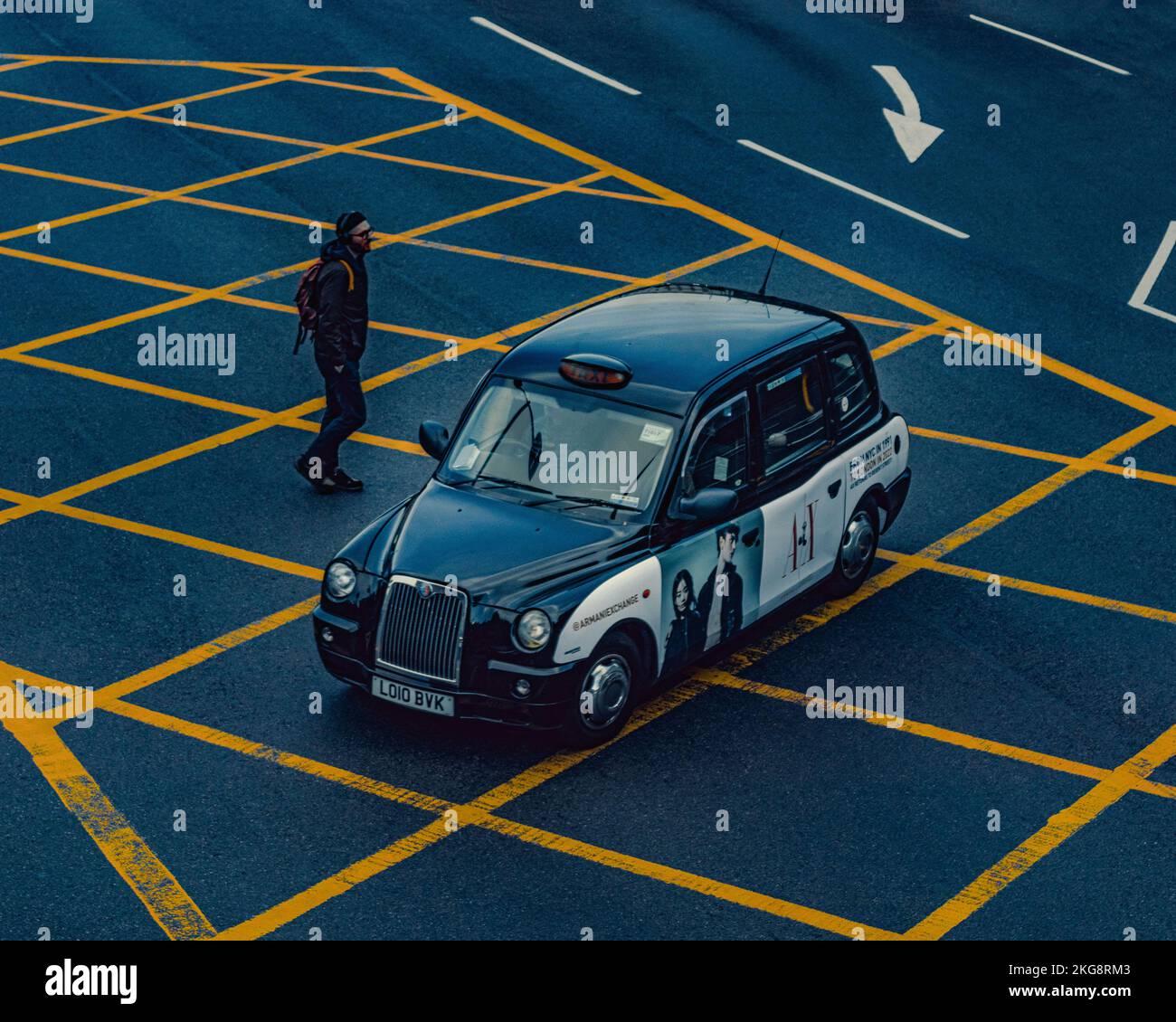 A man crossing the road as a London taxi turns in front of him in a box ...