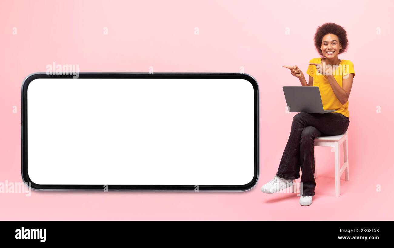 Happy young african american curly lady sit on chair with laptop, show ...