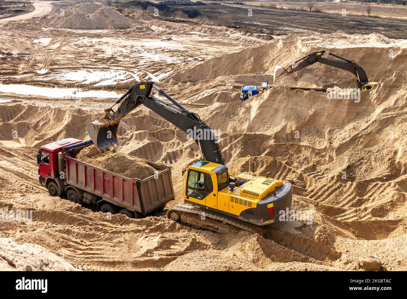 Yellow excavator working with sand at construction site in sunny day ...