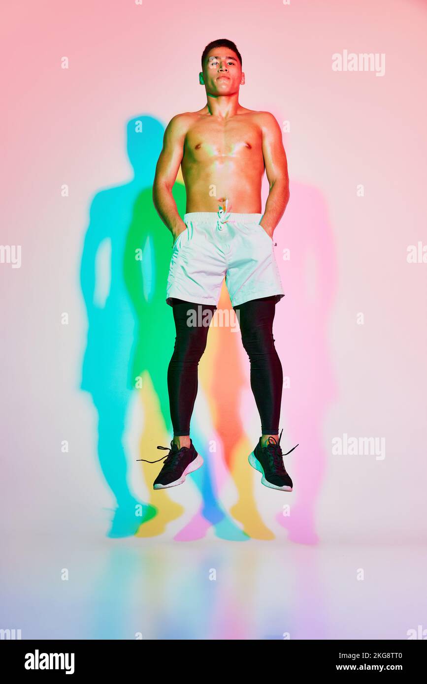 Portrait of young muscular man training, jumping isolated over pink ...