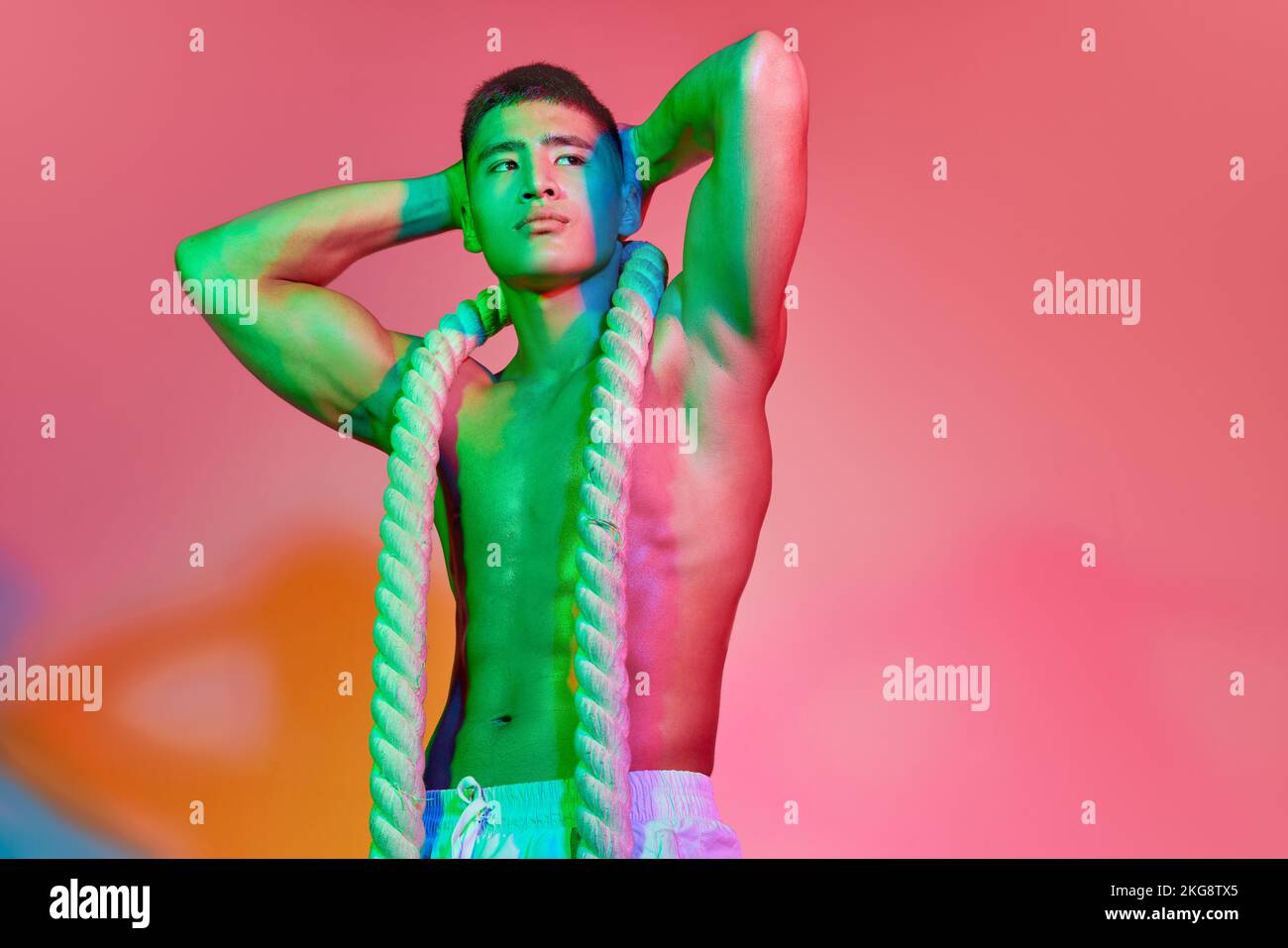 Portrait of young muscular man training, posing with rope isolated over ...
