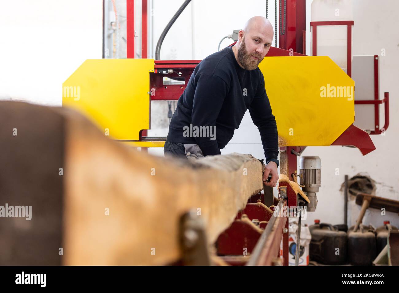 Young man working on the machine for processing the wood, huge wood ...