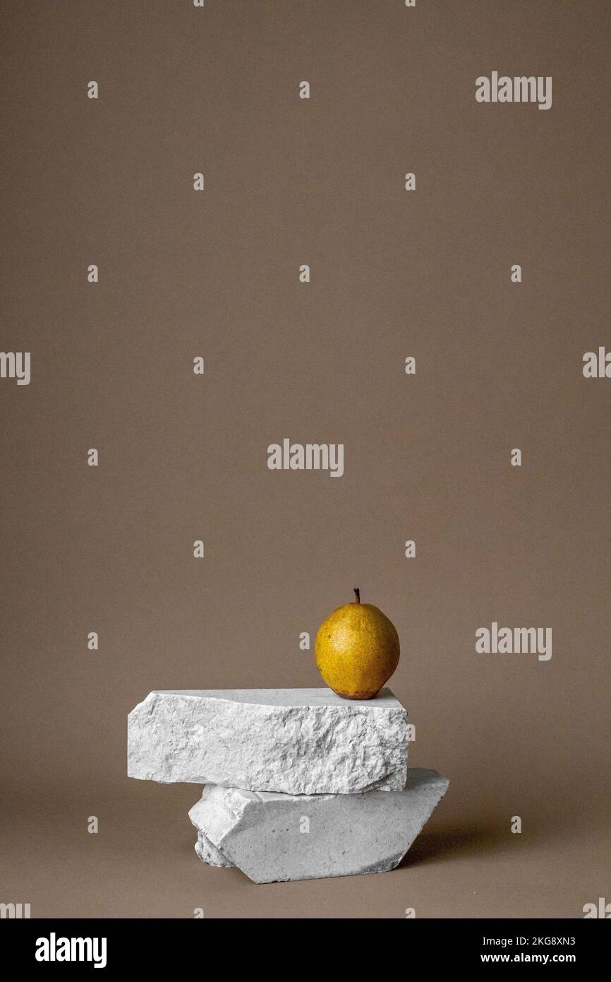 A vertical shot of ripe pear with white rock blocks against light brown ...