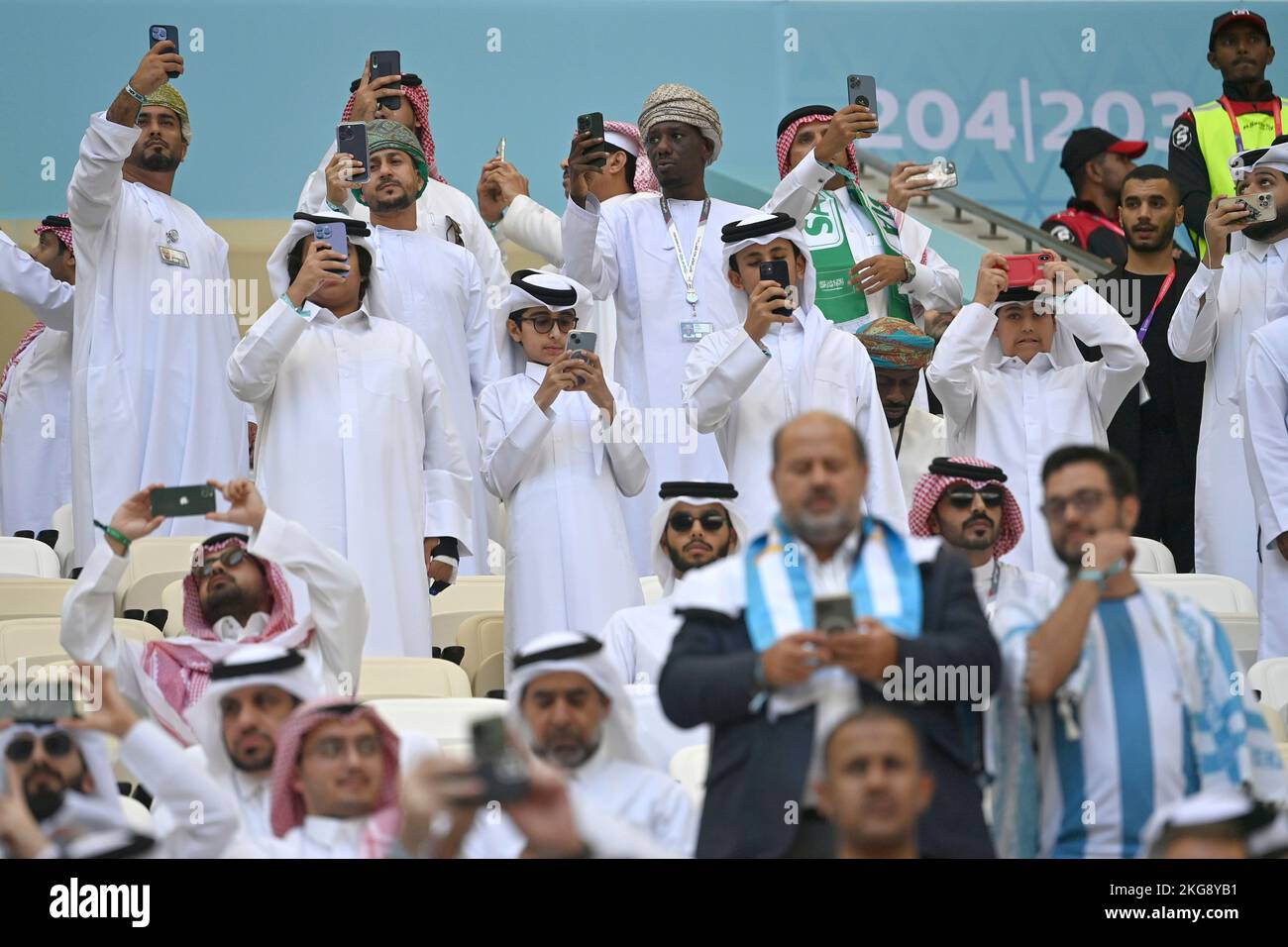 Qataris in their traditional robes on the grandstand, filming and ...