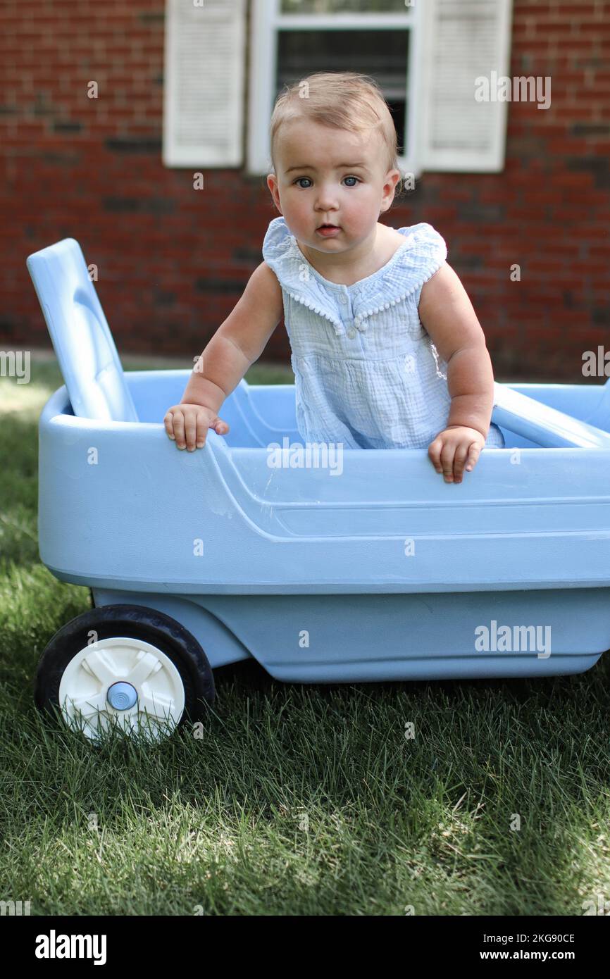 A vertical closeup of a cute 11-month-old baby girl playing in a wagon ...