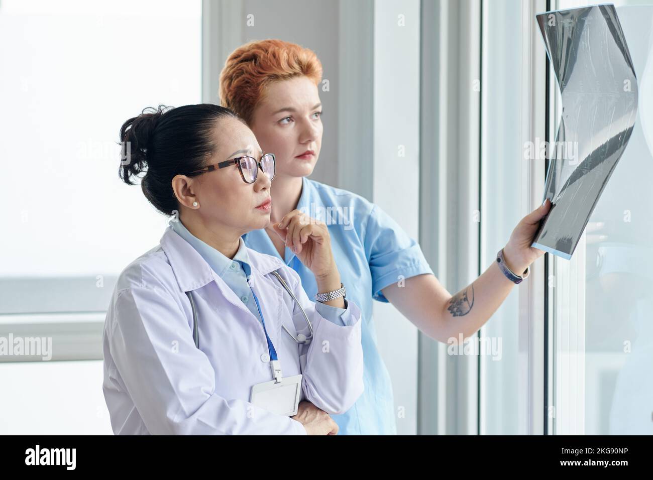 Pensive pulmonologist and radiologist looking at chest x-ray of patient ...