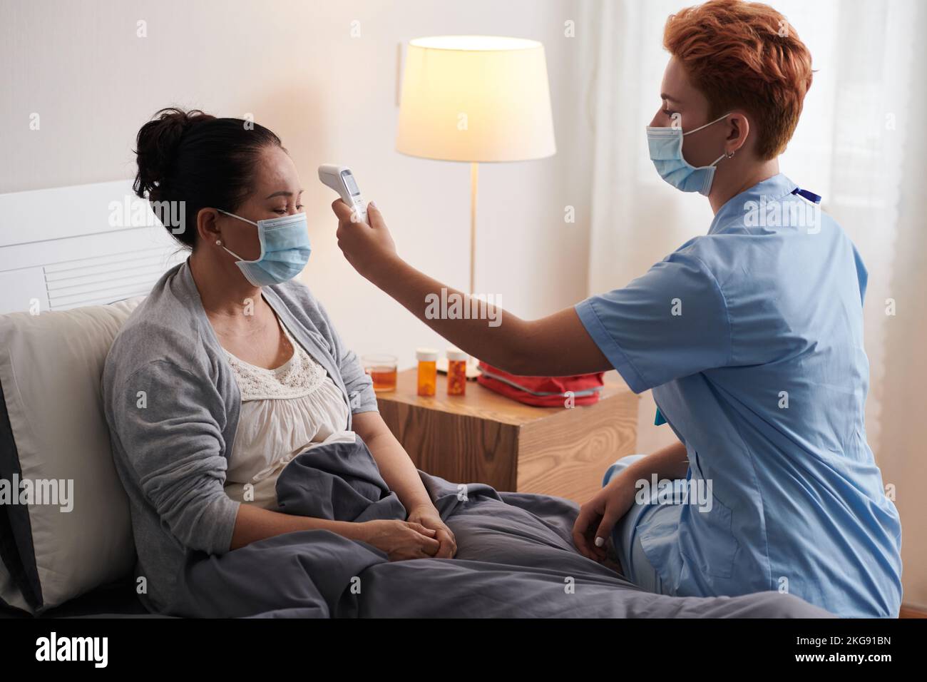 Caregiver using contactless thermometer when measuring body temperature ...