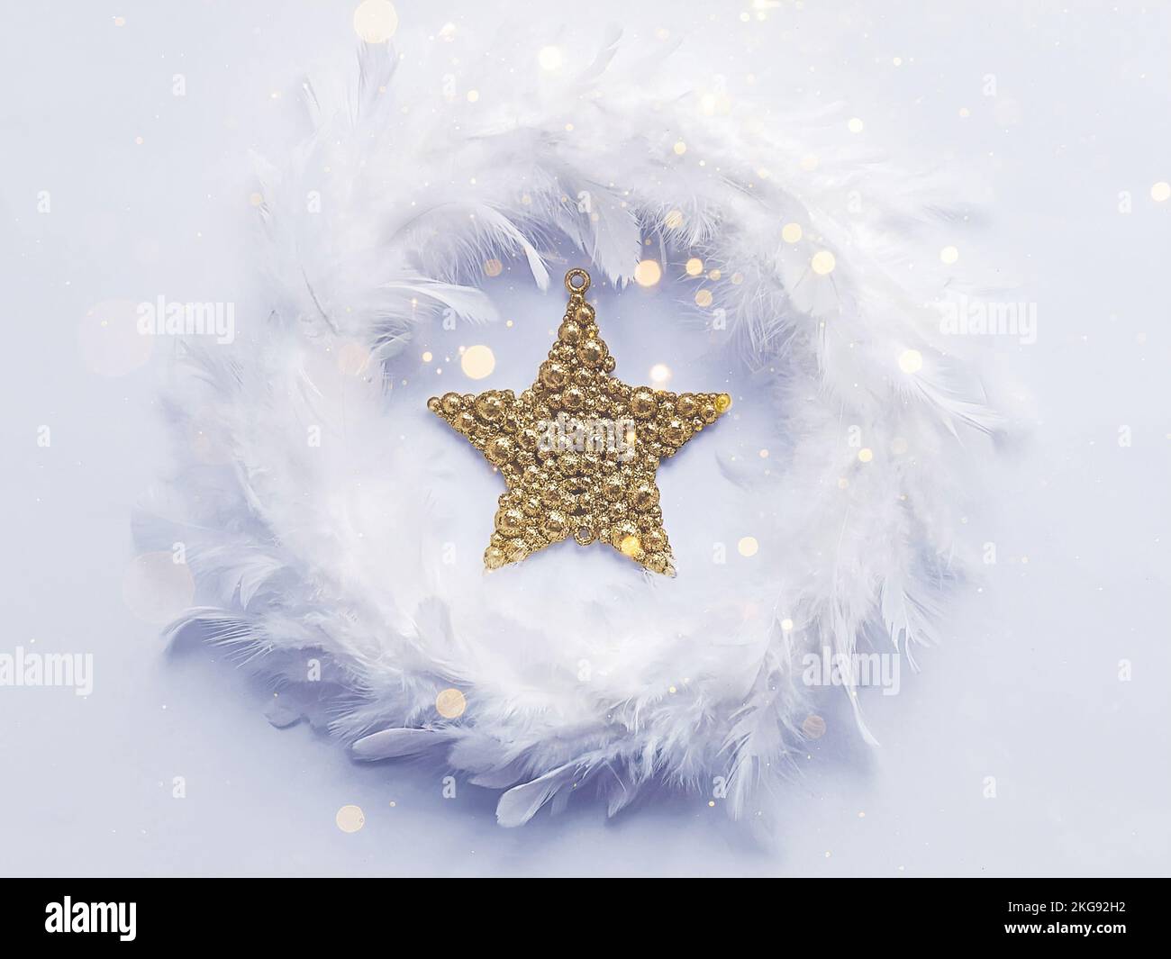 White fuzzy wreath made from feathers with big golden star inside ...