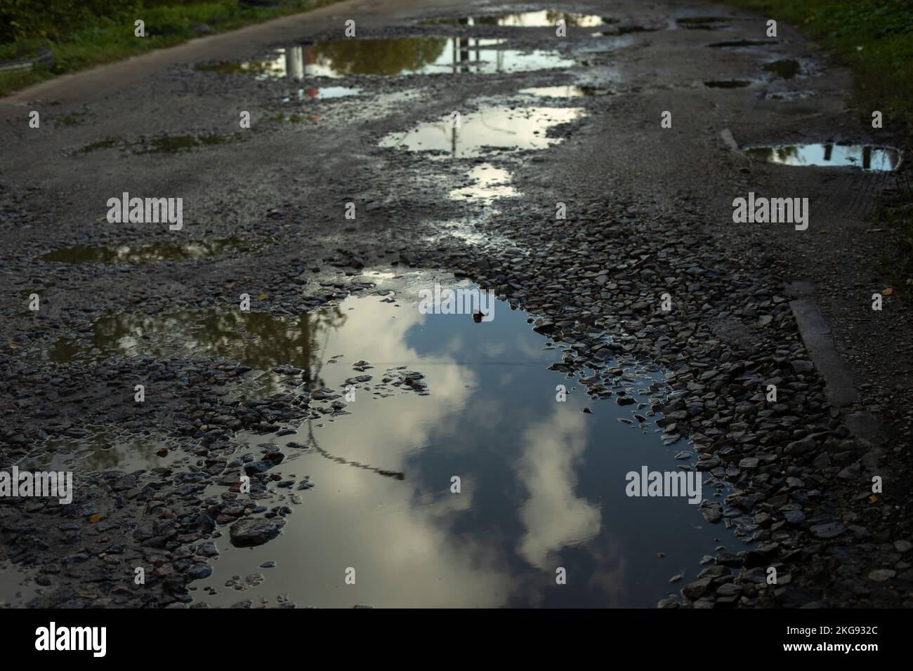 Large puddle on asphalt. Road with pits. Puddles on road. Rural highway ...