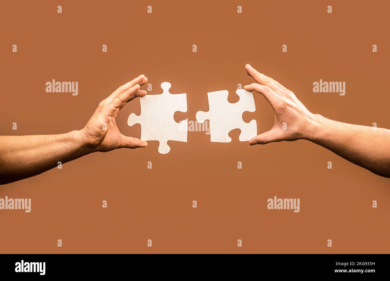 Two hands trying to connect couple puzzle piece on gray background ...