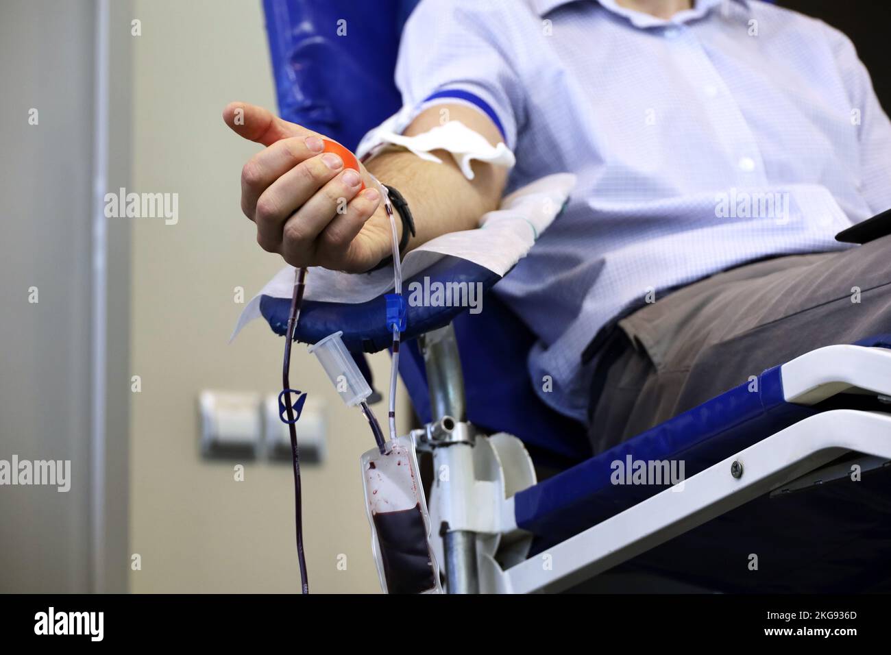 Hand of man blood donor in chair during donation with a blood bag and ...