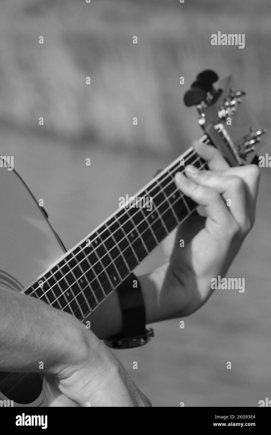 A vertical grayscale shot of a person playing an acoustic guitar Stock ...