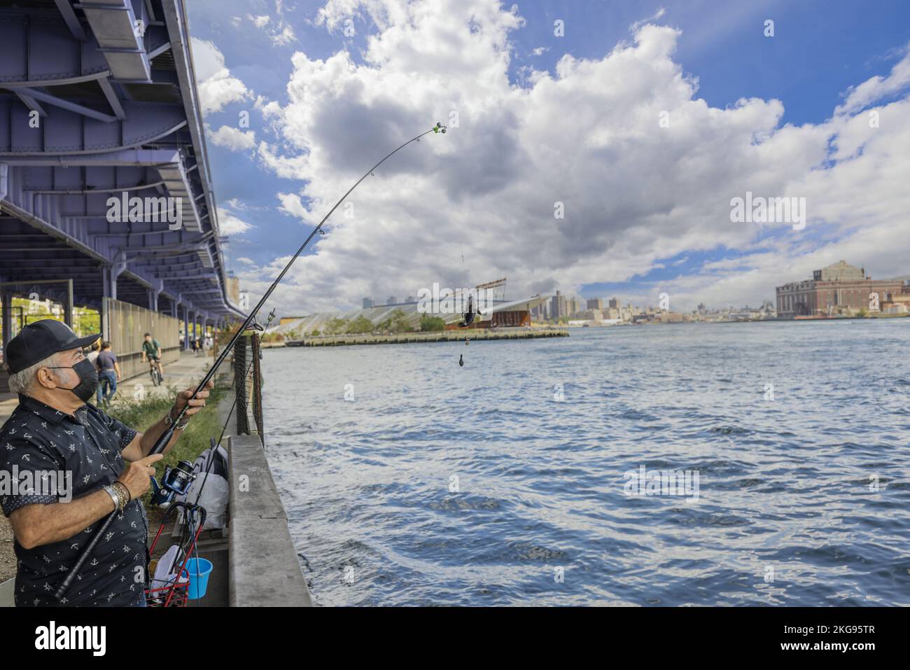 Close up of fisherman with fishing rod under Brooklyn Bridge catching ...