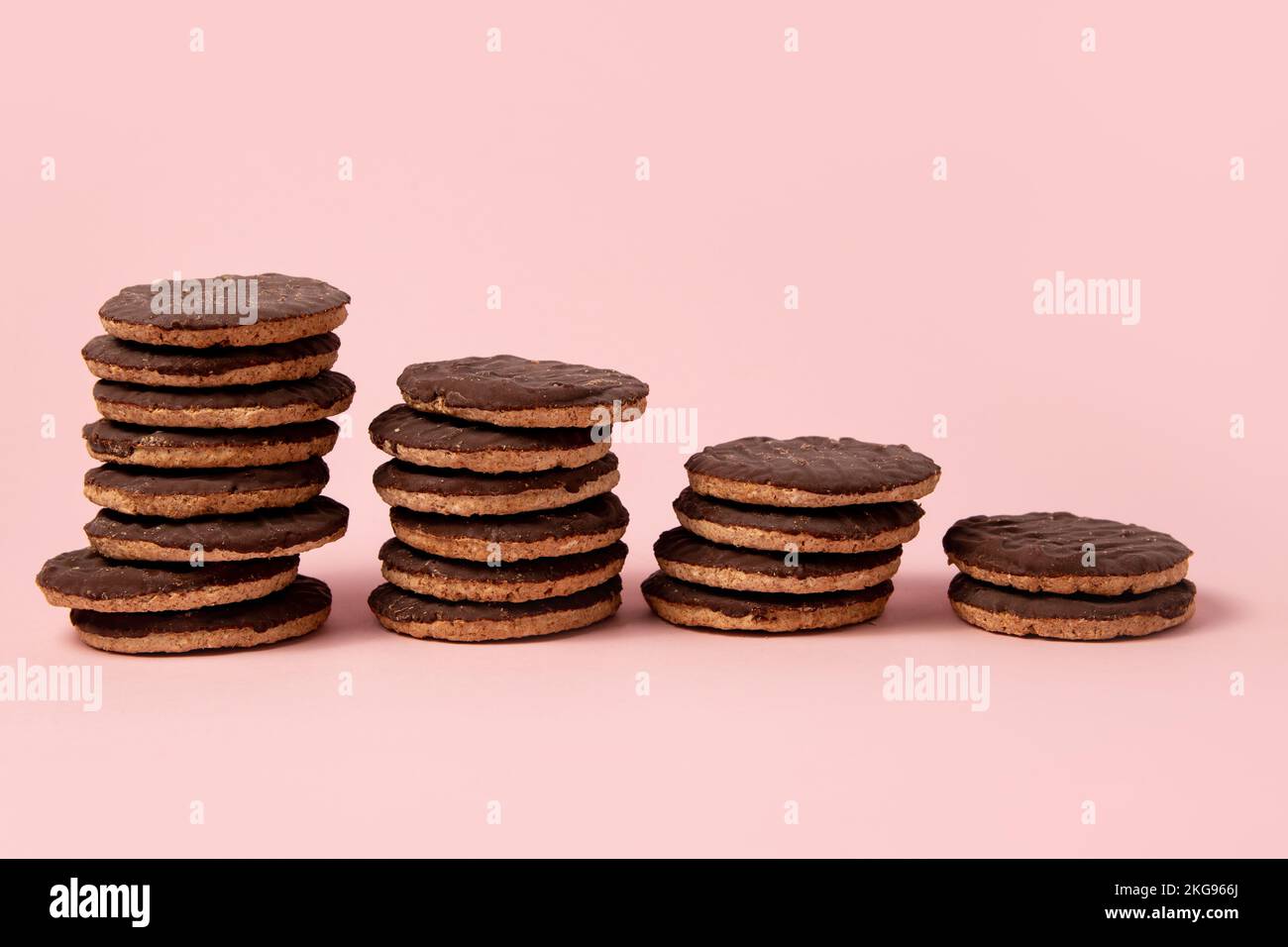 Stacks of chocolate-covered cookies on pink background Stock Photo - Alamy