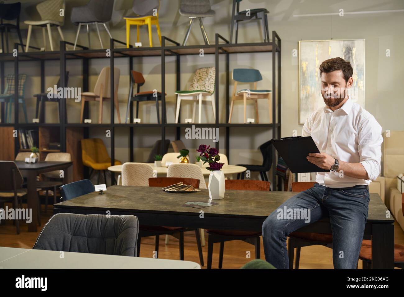 Good-looking busy salesman leaning on table, while working in expo ...