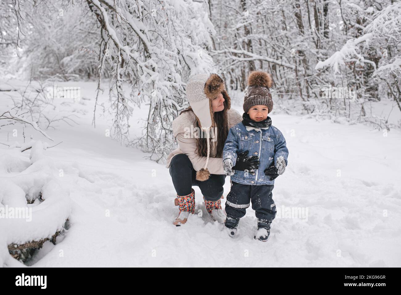 Mom and son are walking in the snow in the winter forest Stock Photo ...