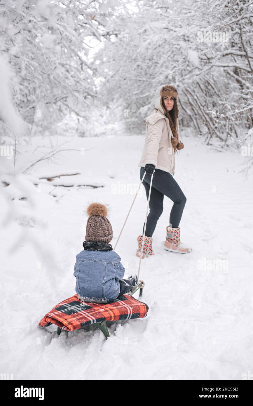 Mom and son are walking in the snow in the winter forest Stock Photo ...
