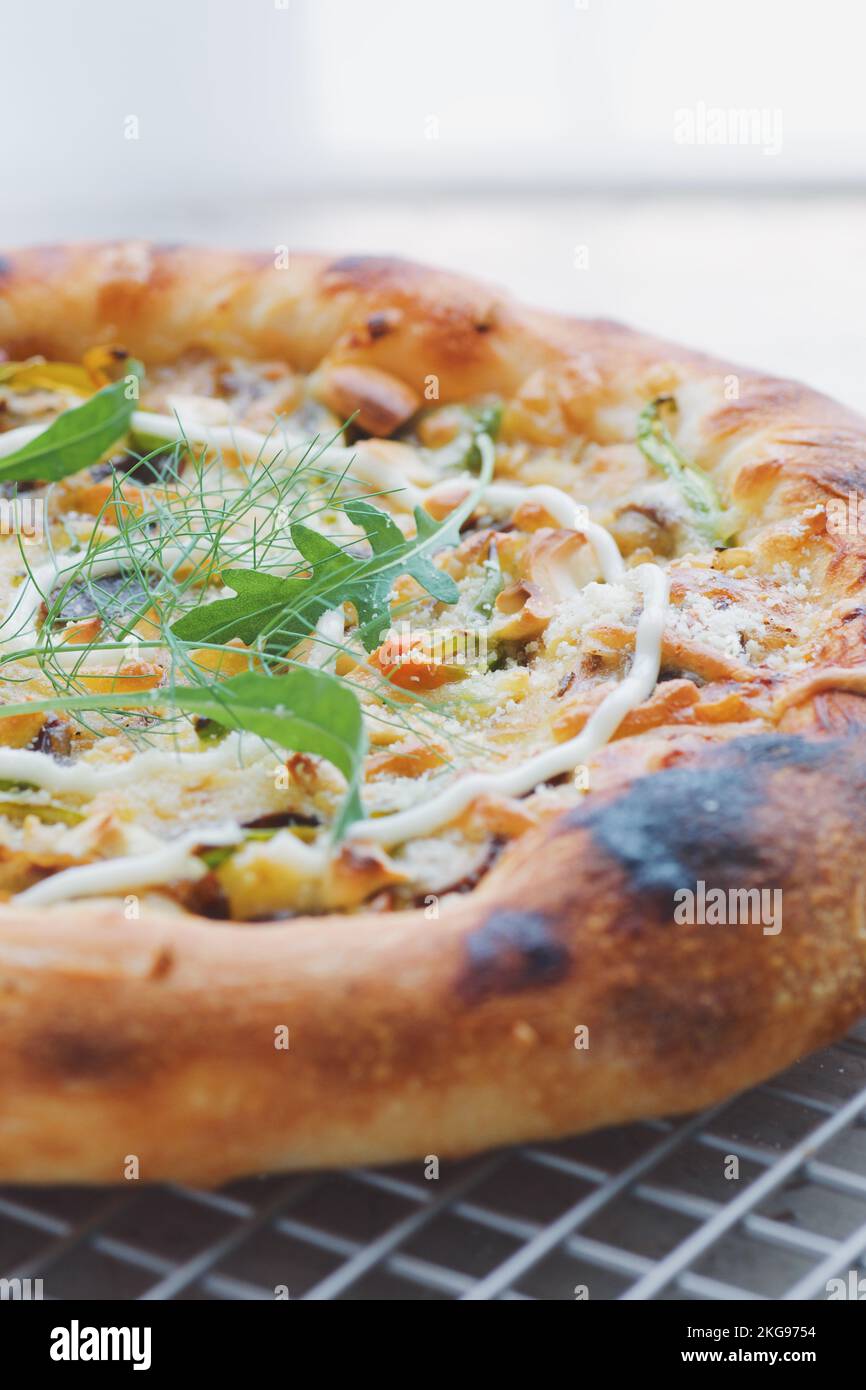 A vertical closeup shot of a delicious pizza with cheese and greens ...