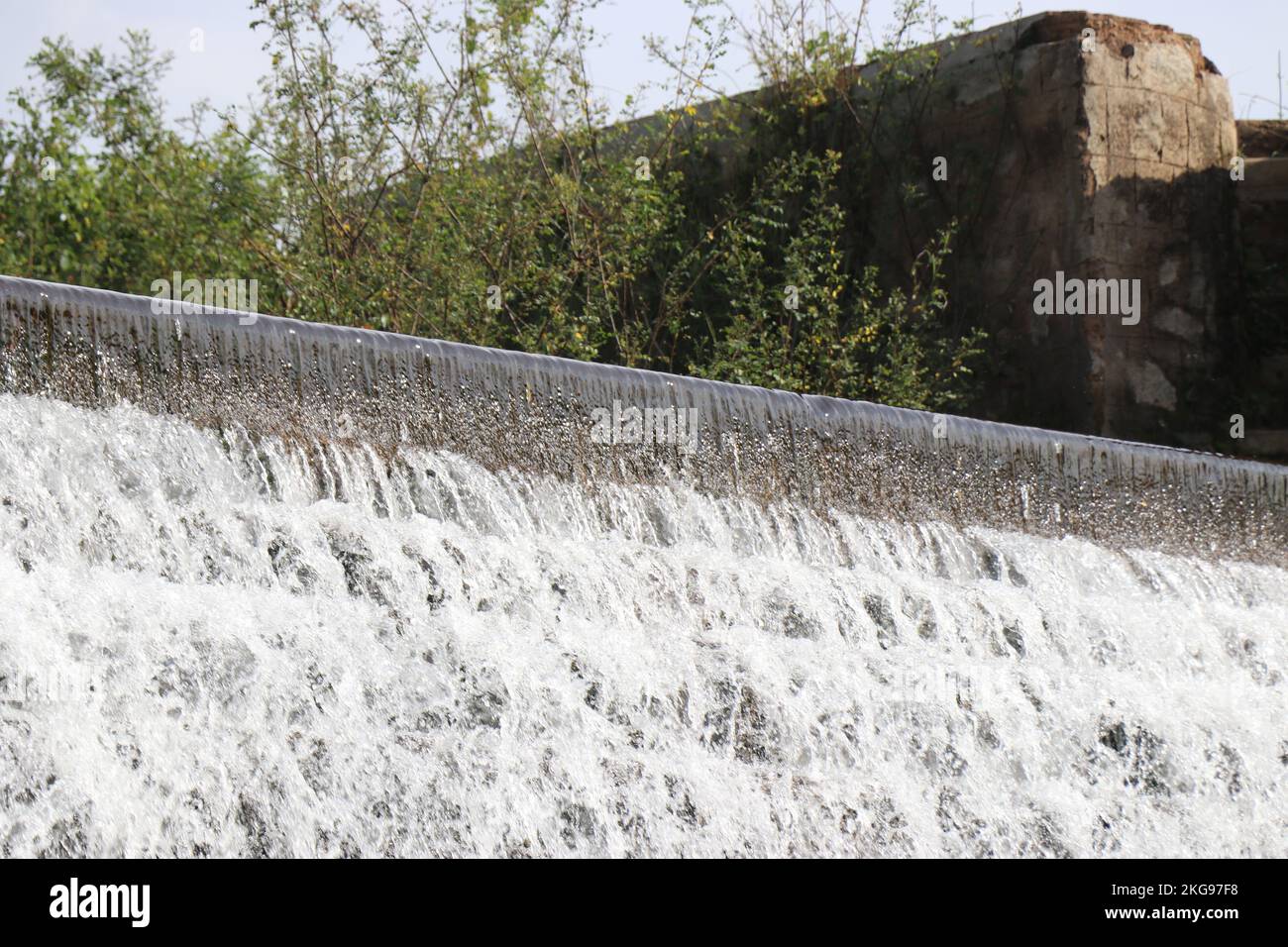 Fresh water flows through steps made of brick on a overflow dam on a ...
