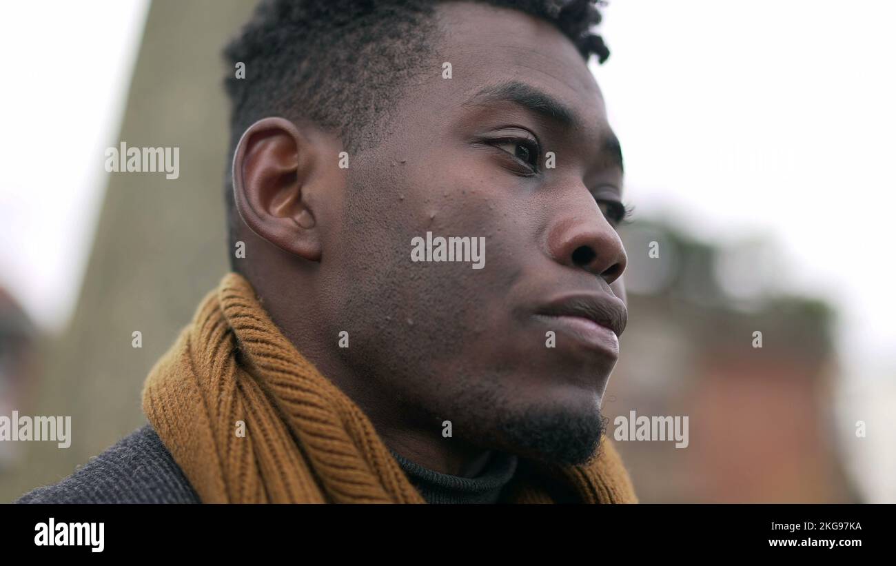 Serious black African man standing at park wearing winter clothing ...