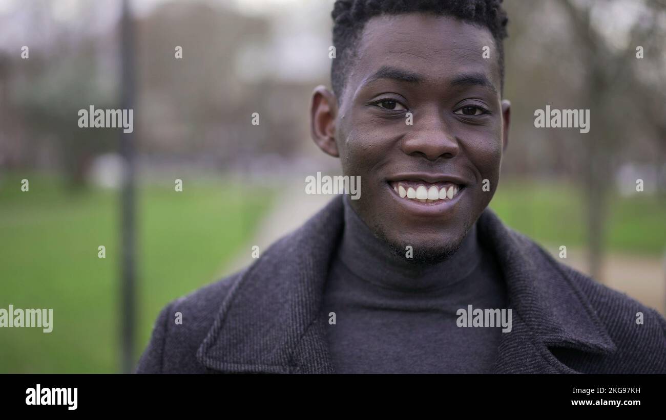 Satisfied young black African man walking outside at park nature ...