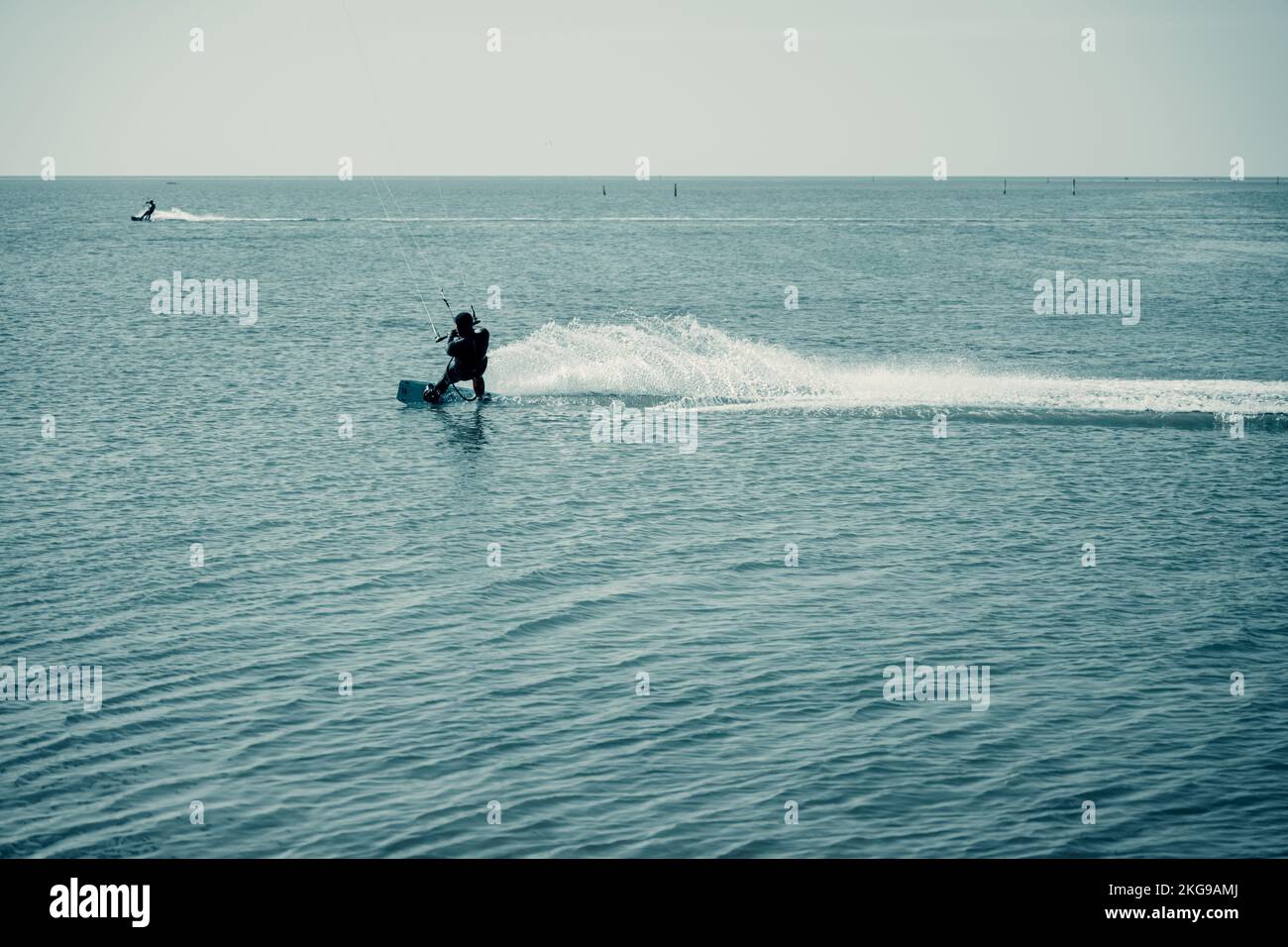 Wind surfer on flat water riding with clear blue sky and beach on the ...