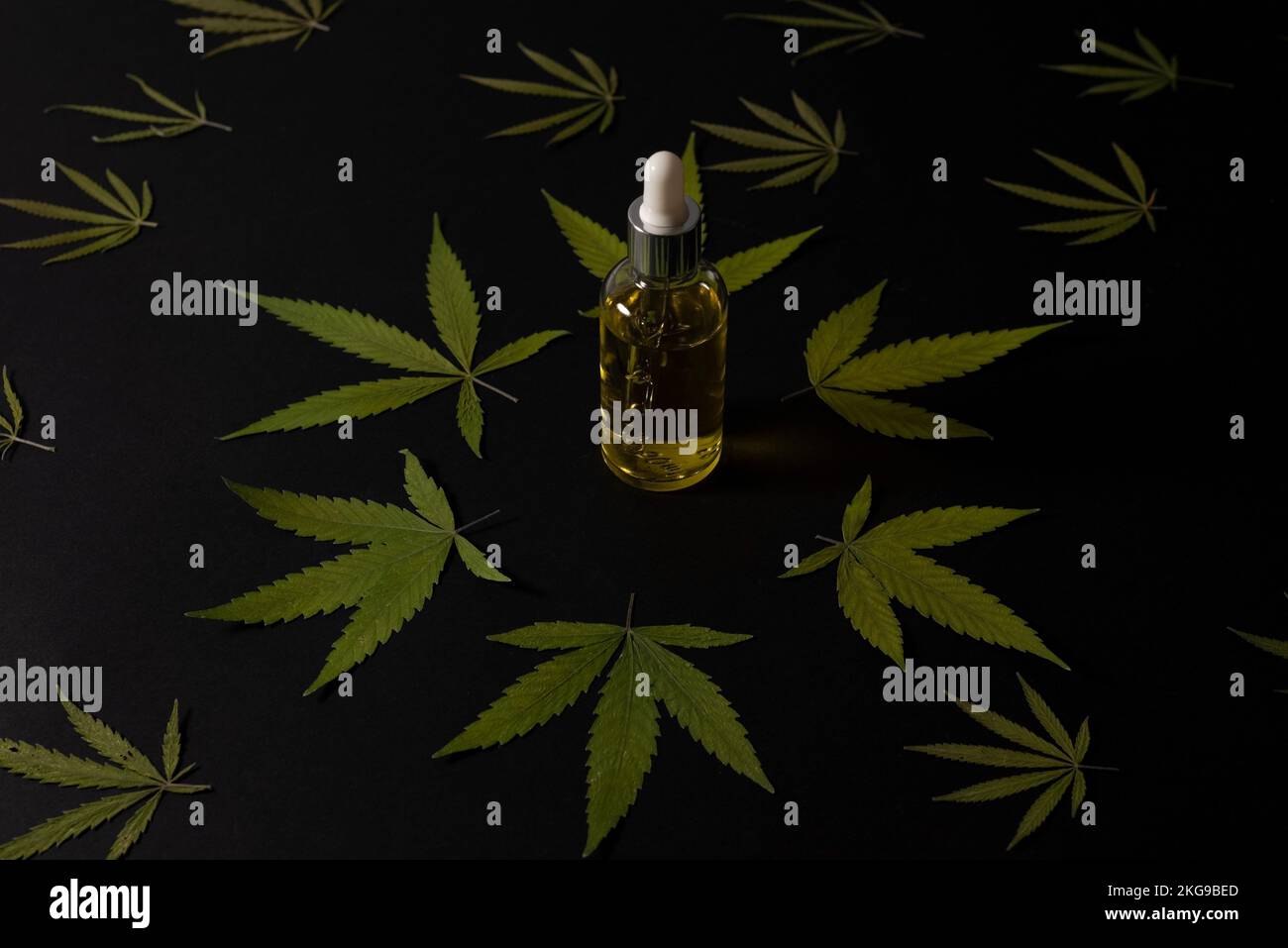 Various glass bottles with CBD oil, THC tincture and hemp leaves on a ...