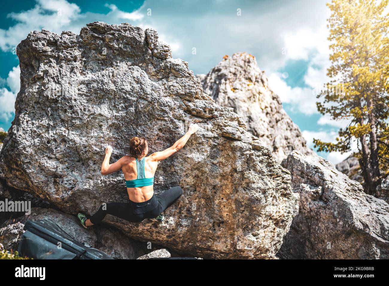 Description: Sporty woman climbs on boulder block in the afternoon ...