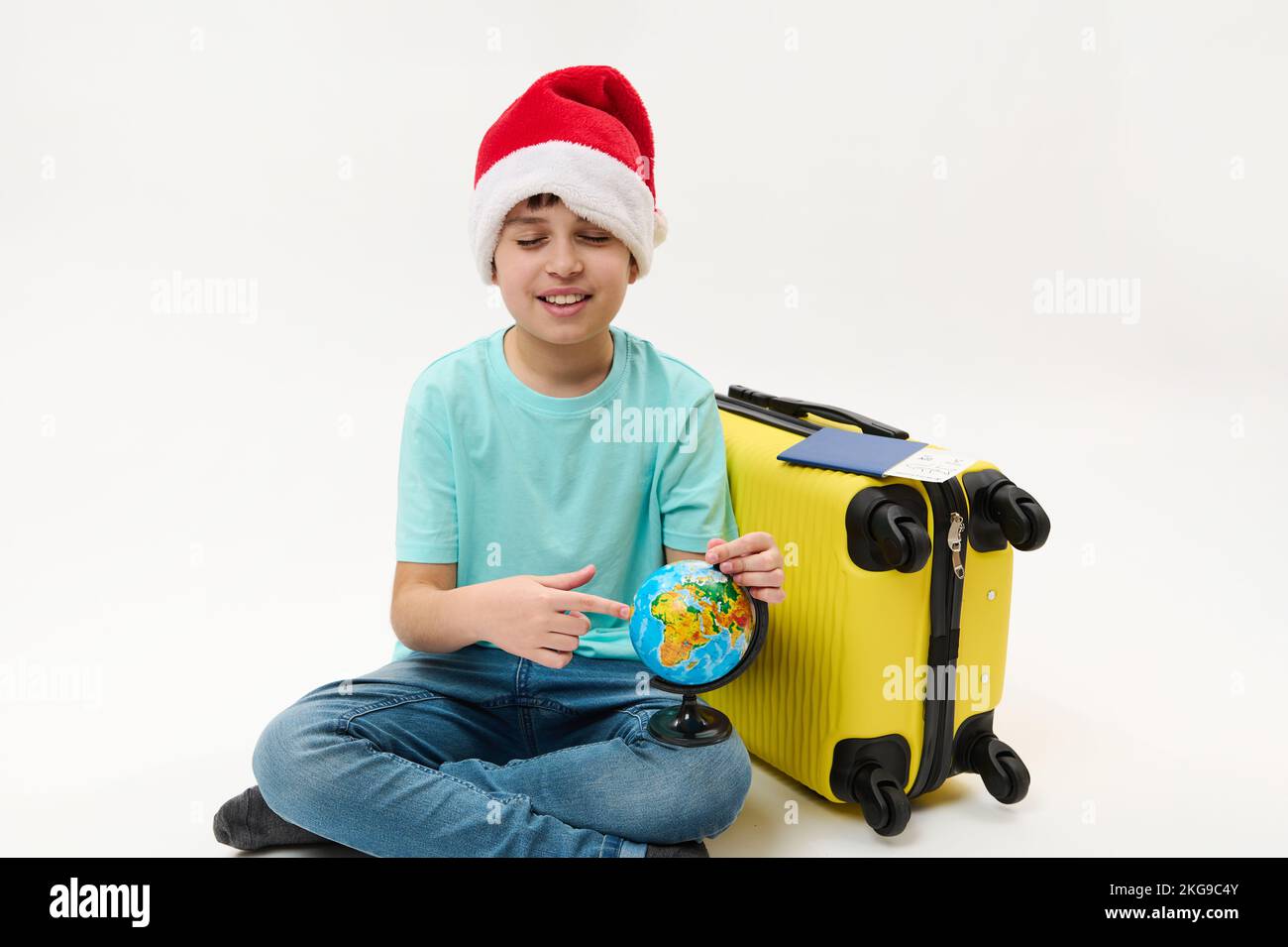 Isolated portrait of a child boy in Santa hat, pointing on travel ...