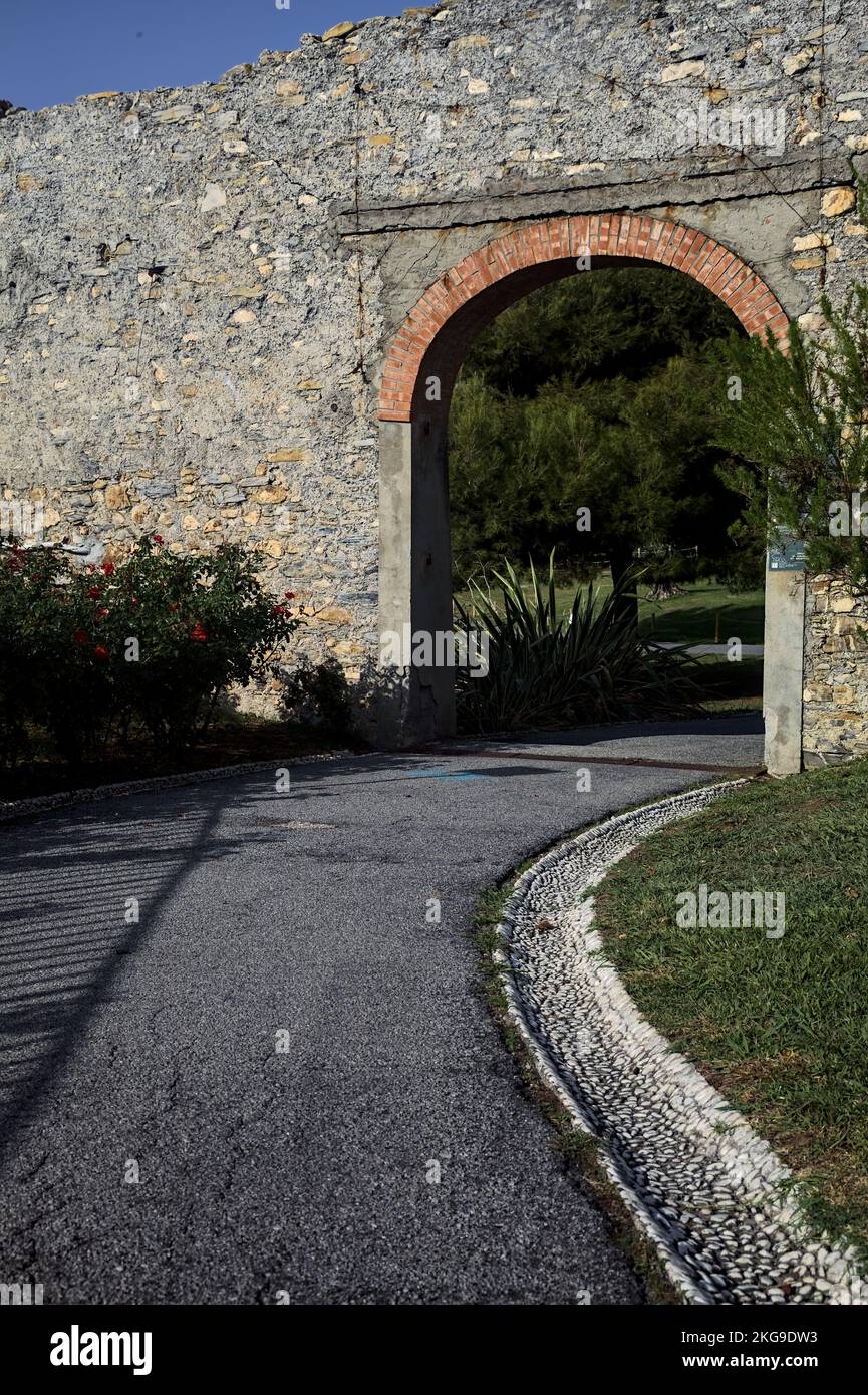 Path going through an arch of an ancient bounday wall in a park Stock ...