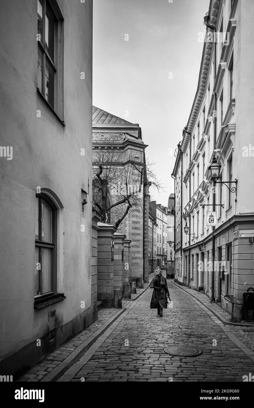rear view of woman walking through the streets of old town Gamla Stan ...