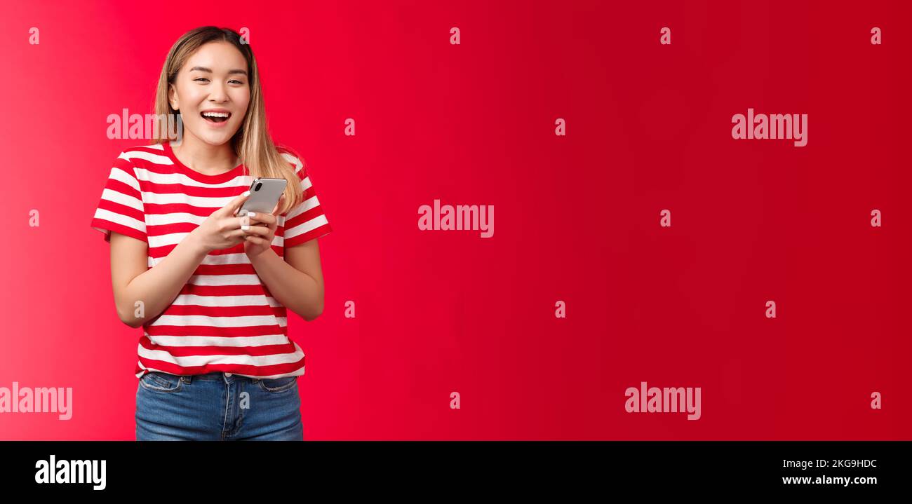 Happy cheerful asian blond girl laughing using smartphone, girl hold ...