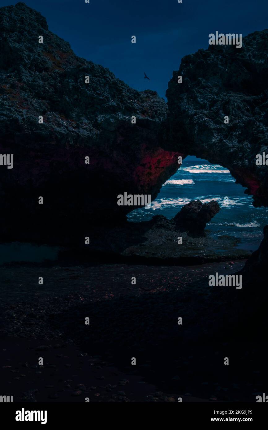 Dark and mysterious coastal scene with large rock formations on beach ...